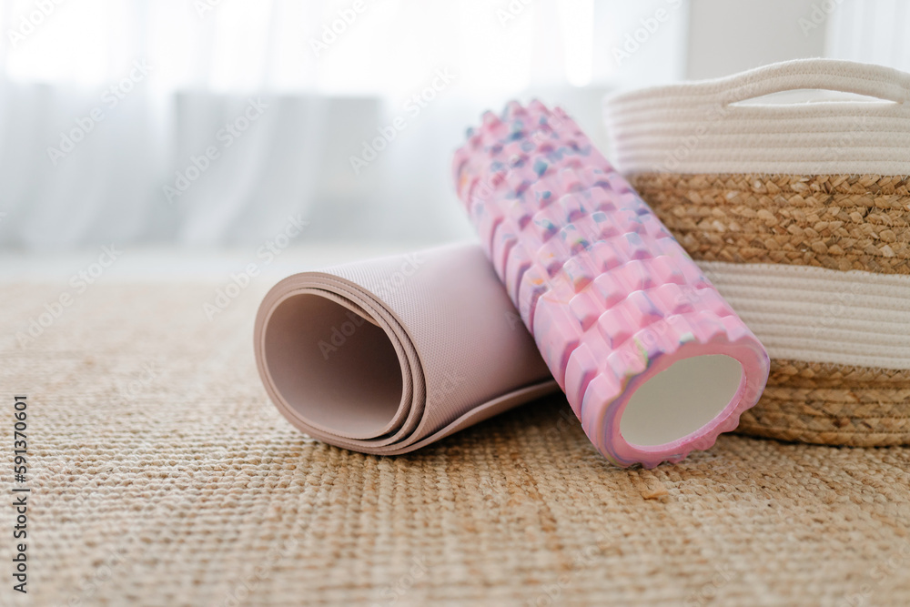 A pink foam massage roller and yoga mat at floor in living room. Foam ...