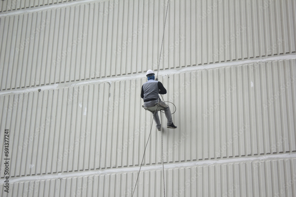 working man on the high building . Building maintenance cleaning and ...