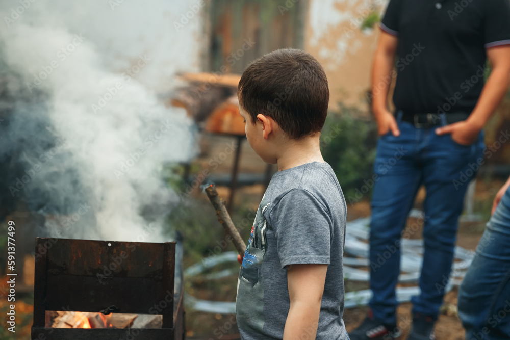 Child boy playing with smoking wooden stick outdoors. Child watching ...