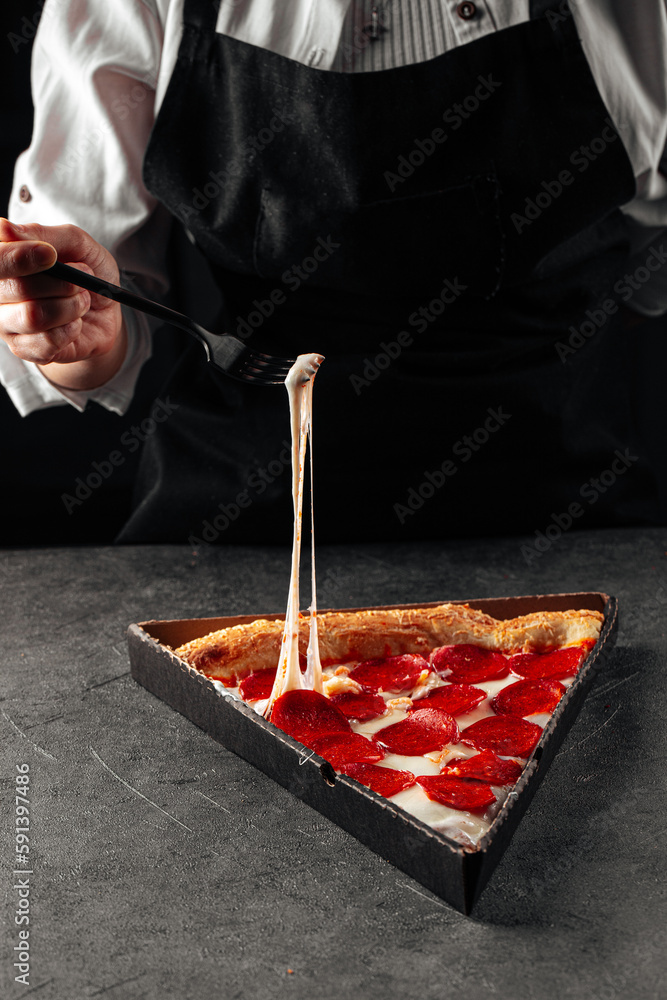 Pulling cheese from slice of pepperoni pizza with fork Stock Photo ...