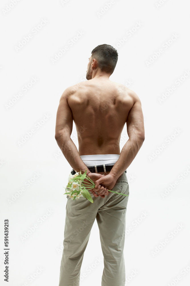 One shirtless muscular man holding bouquet of flowers behind the back ...