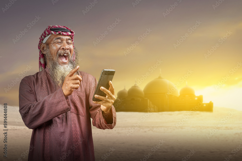 Muslim man with a beard wearing keffiyeh with agal using mobile phone ...