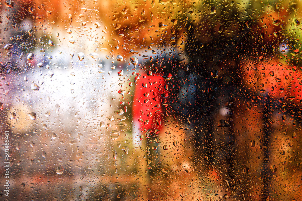 View through a glass window with raindrops on a blurred silhouette of a ...