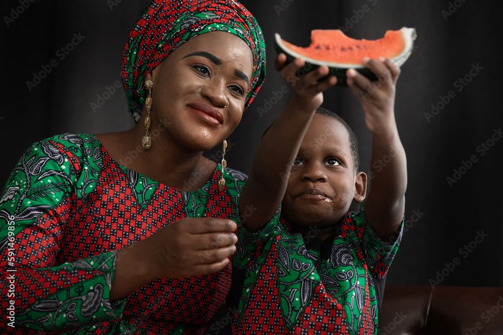 African mother and son in traditional clothes on black background, boy ...