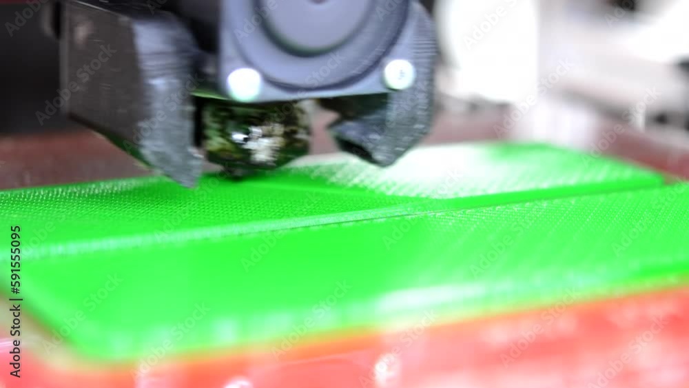 3D printer. 3d printer printing close-up. Molten plastic flowing out of extruder and forming ...