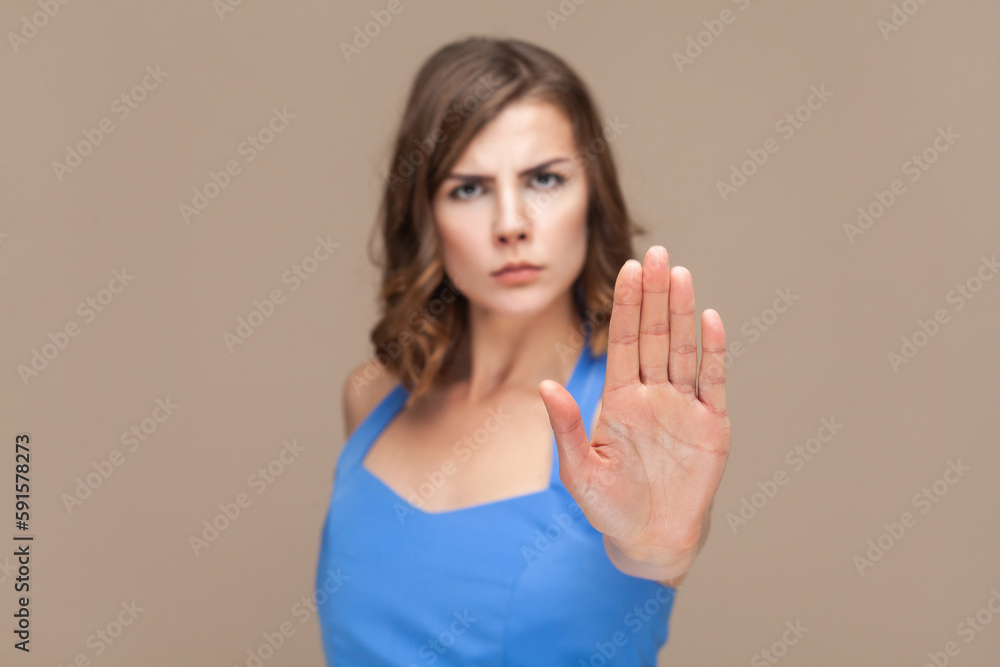 Portrait of serious strict woman with wavy hair showing stop sign ...