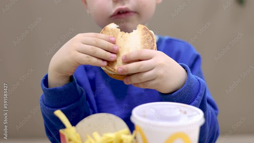 adorable cute preschooler boy child eating junk food and drink ...