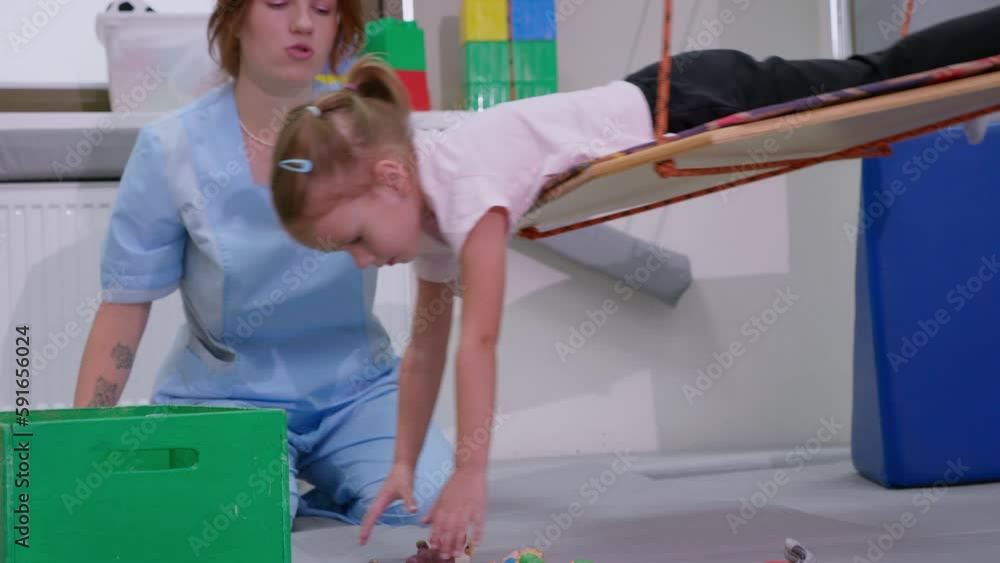 Child with physiotherapist on swing in sensory integration room. Little ...
