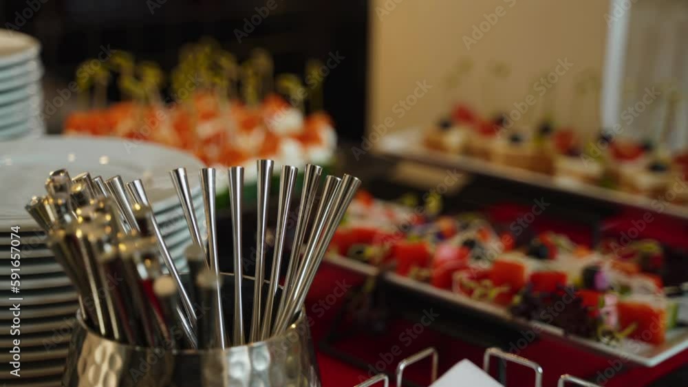 Stack of empty plates and metal cutlery in bucket on table with ...
