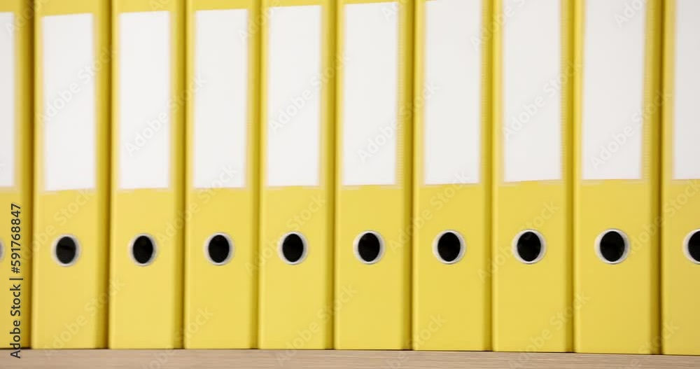 Organized structure of yellow ring binders put on rack shelves in row ...
