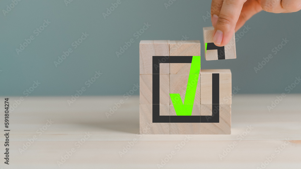 Hand placing wooden cube with green checkmark icon. Goals achievement ...