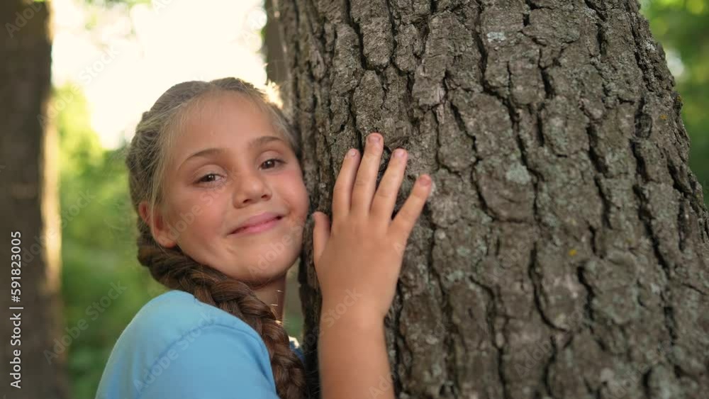 a small child ecologist hugs the trunk of a tree bark in a forest park ...