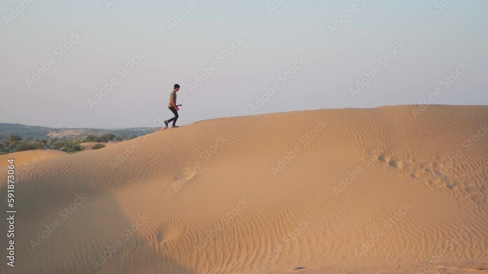 Wide angle shot of Indian man running on top of the sand dune at Thar ...