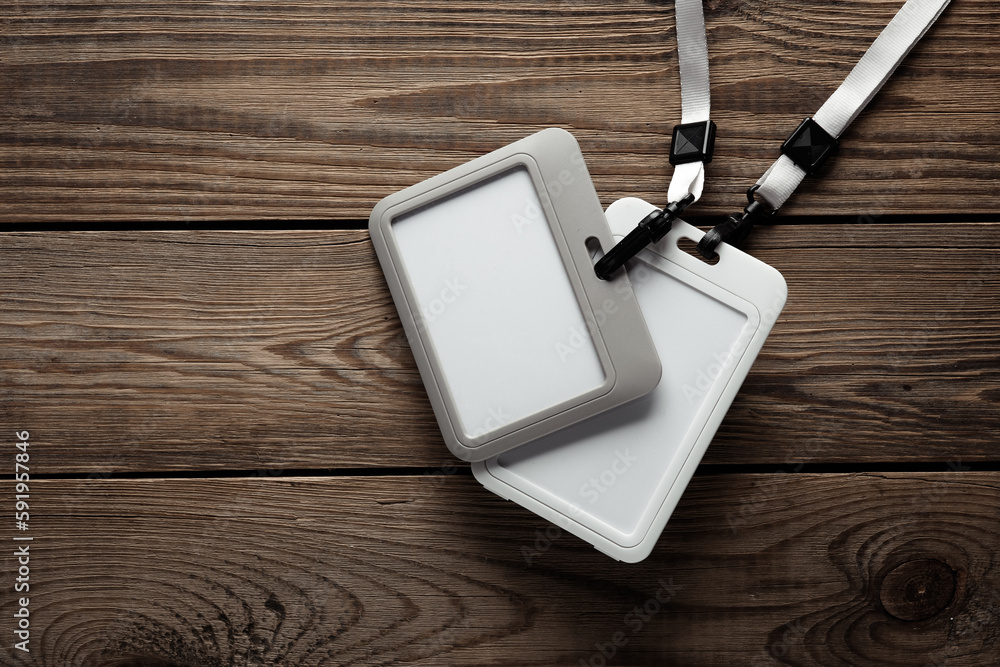 Blank plastic Id card badges with belt on wooden table. Template for ...