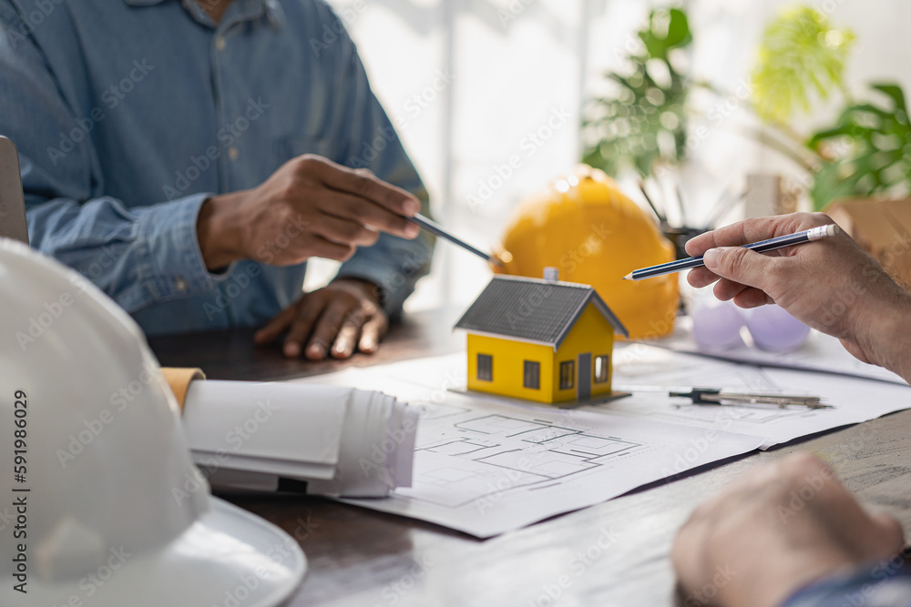 Engineer pointing at blueprint and using laptop to draw project design ...
