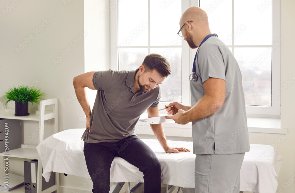 Patient with lower back pain comes to the doctor. Young man suffering ...