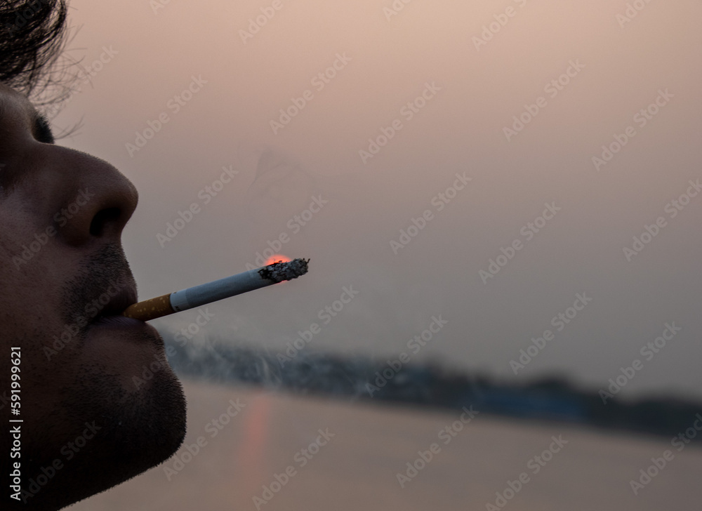 Man smoking a cigarette on a sunset background. Cigarette addiction ...