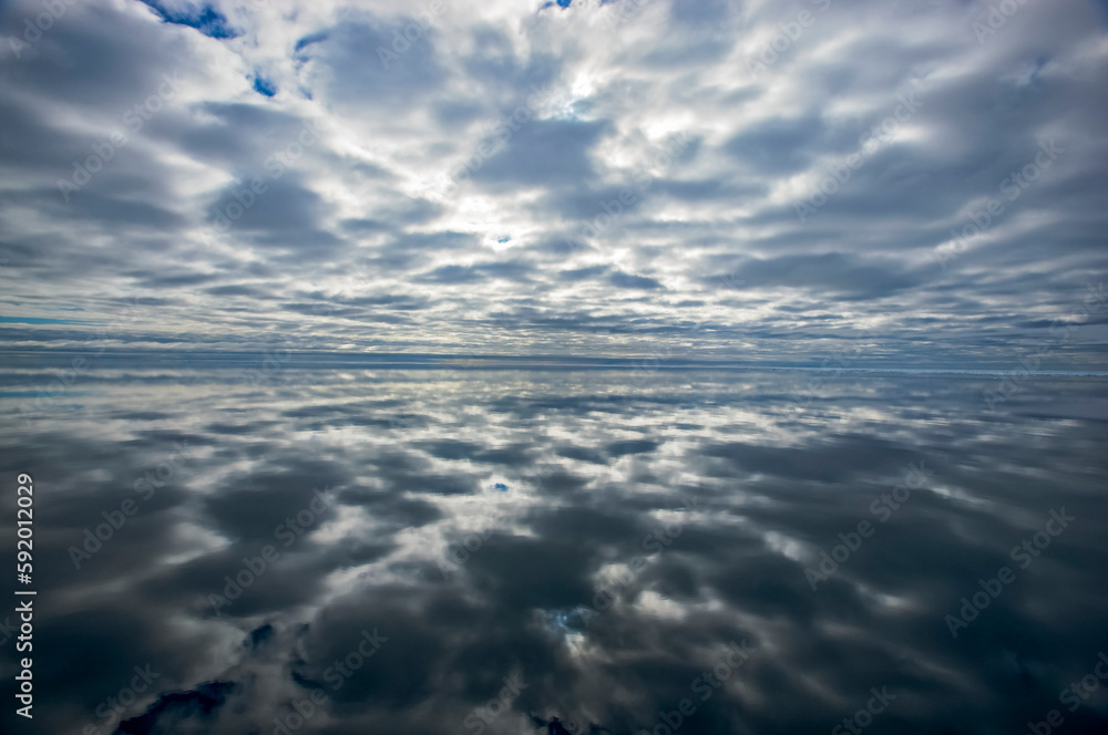 Foto de Mirror image of a cloudy sky reflected on the surface of ocean ...