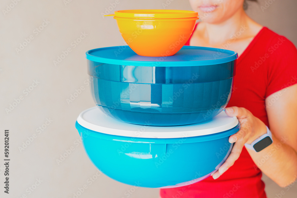Person carries a pile of plastic containers Stock Photo | Adobe Stock