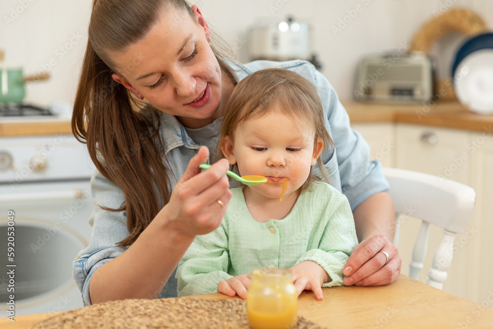 Happy family at home. Mother feeding her baby girl from spoon in ...