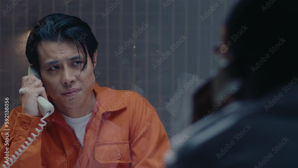 AgressiveAsian prisoner in orange jumpsuit having talk with detective ...