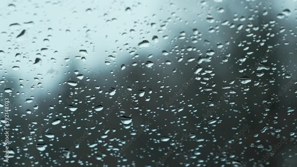Snow fall on window and melting into water drops on glass in the forest ...