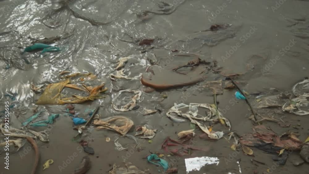 Cinematic shot of plastic waste buried in the sand of this beach in ...