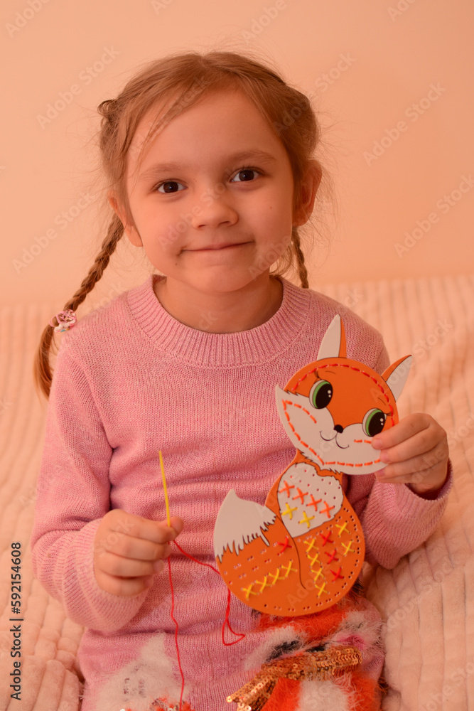 The child learns to embroider with a cross. A cute little girl with ...