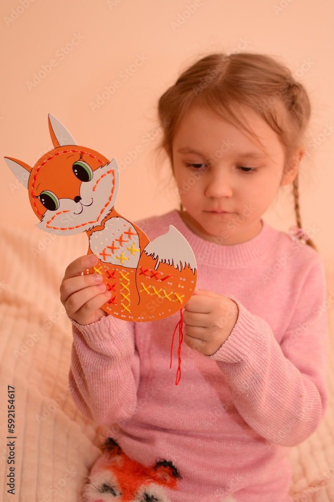 The child learns to embroider with a cross. A cute little girl with ...