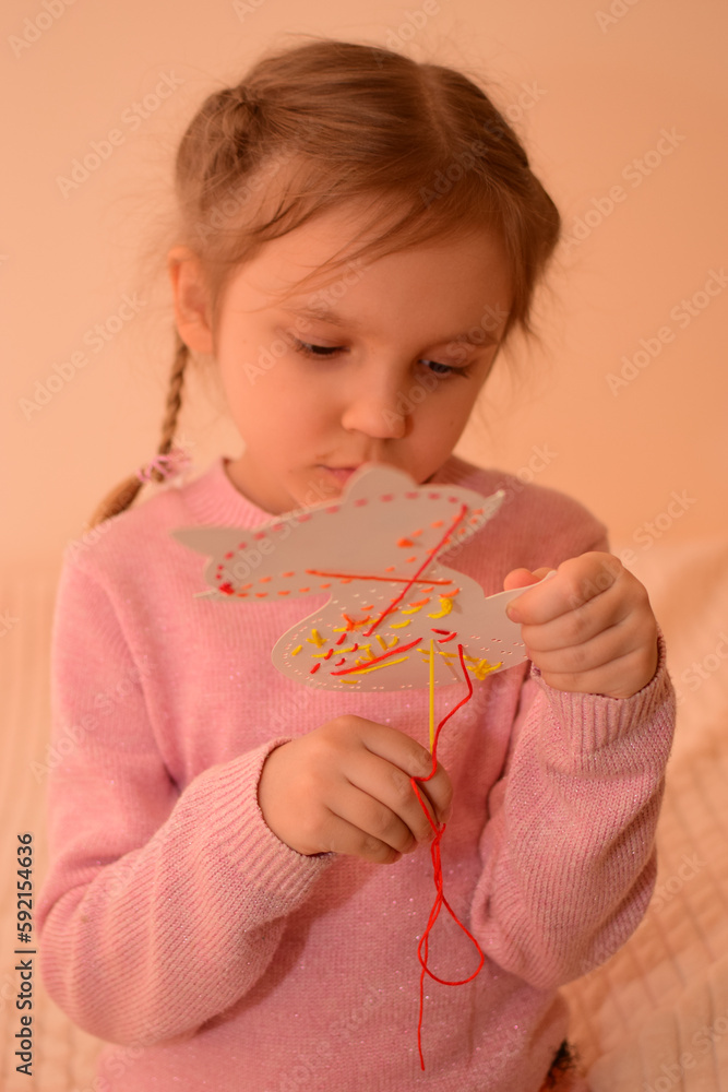 The child learns to embroider with a cross. A cute little girl with ...