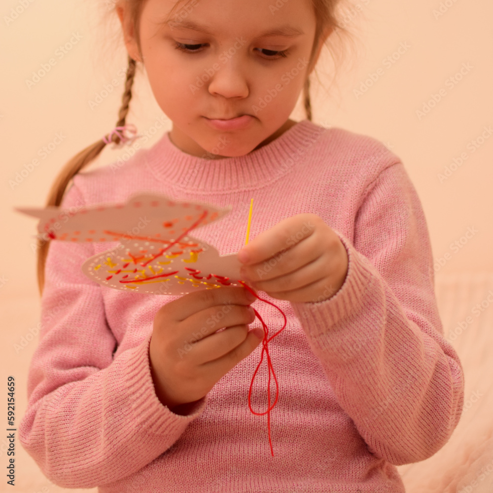 The child learns to embroider with a cross. A cute little girl with ...