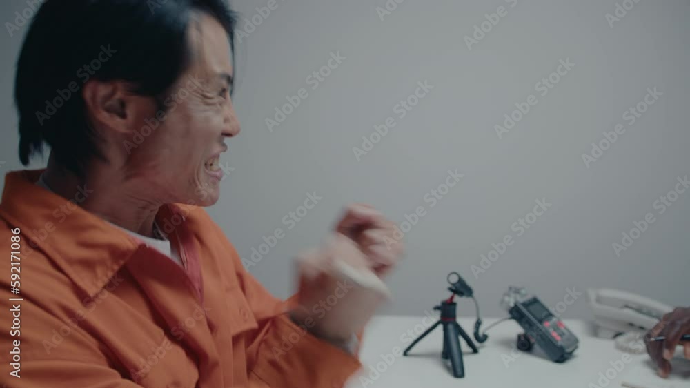 Angry Asian criminal in handcuffs and orange jumpsuit yelling ...