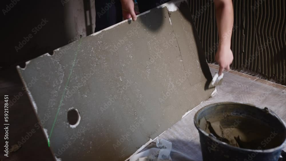 The process of applying tile adhesive to a large porcelain stoneware ...