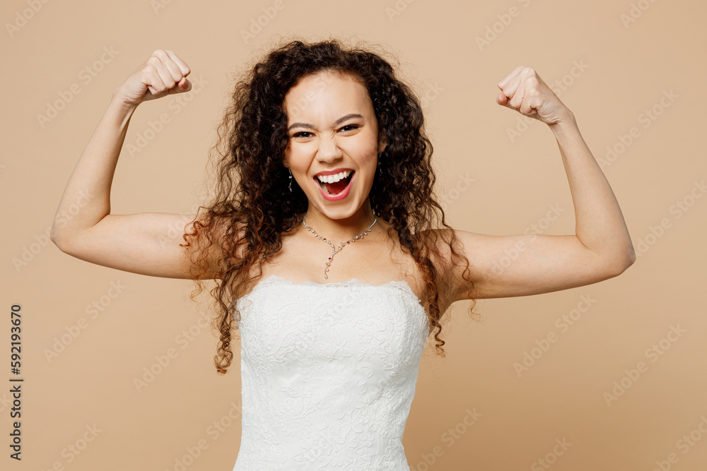 Happy young woman bride wear white wedding dress posing showing muscles ...