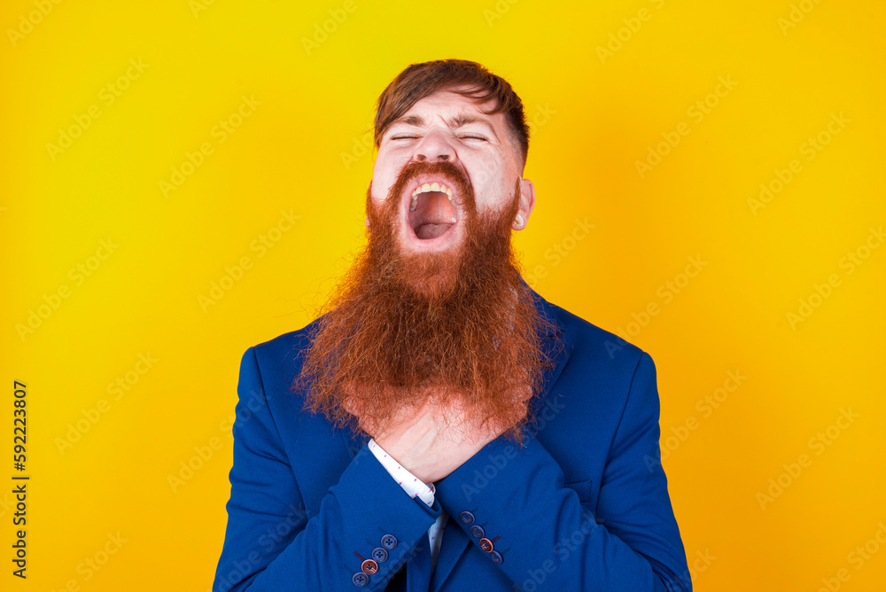 red haired man wearing blue suit over yellow studio background shouting suffocate because ...
