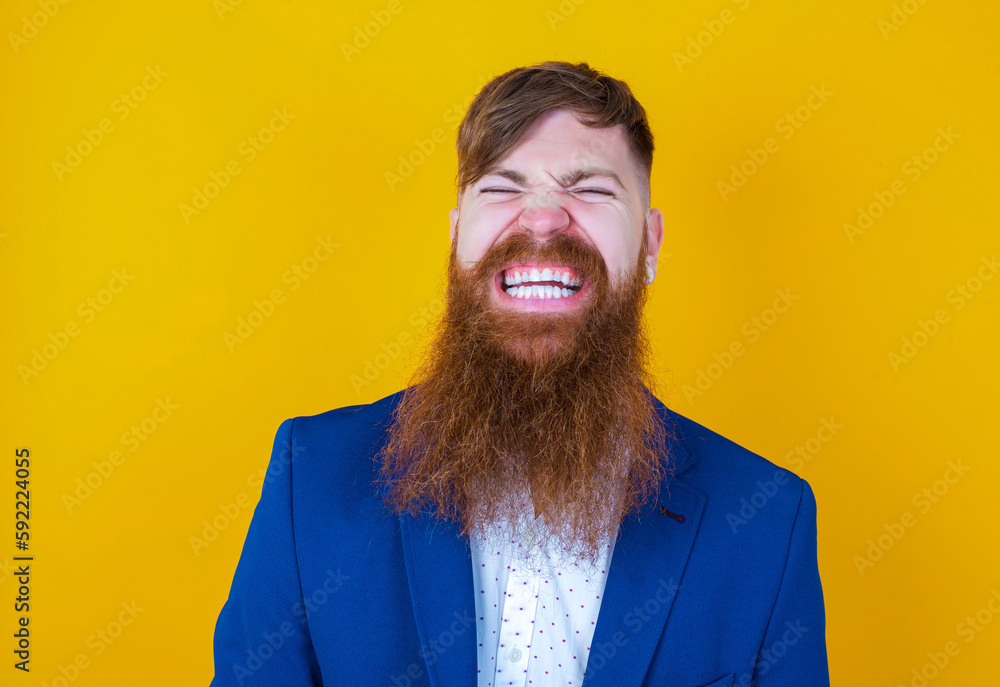red haired man wearing blue suit over yellow studio background keeps ...