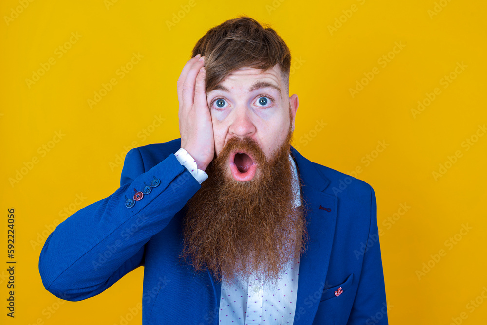 Embarrassed red haired man wearing blue suit over yellow studio ...