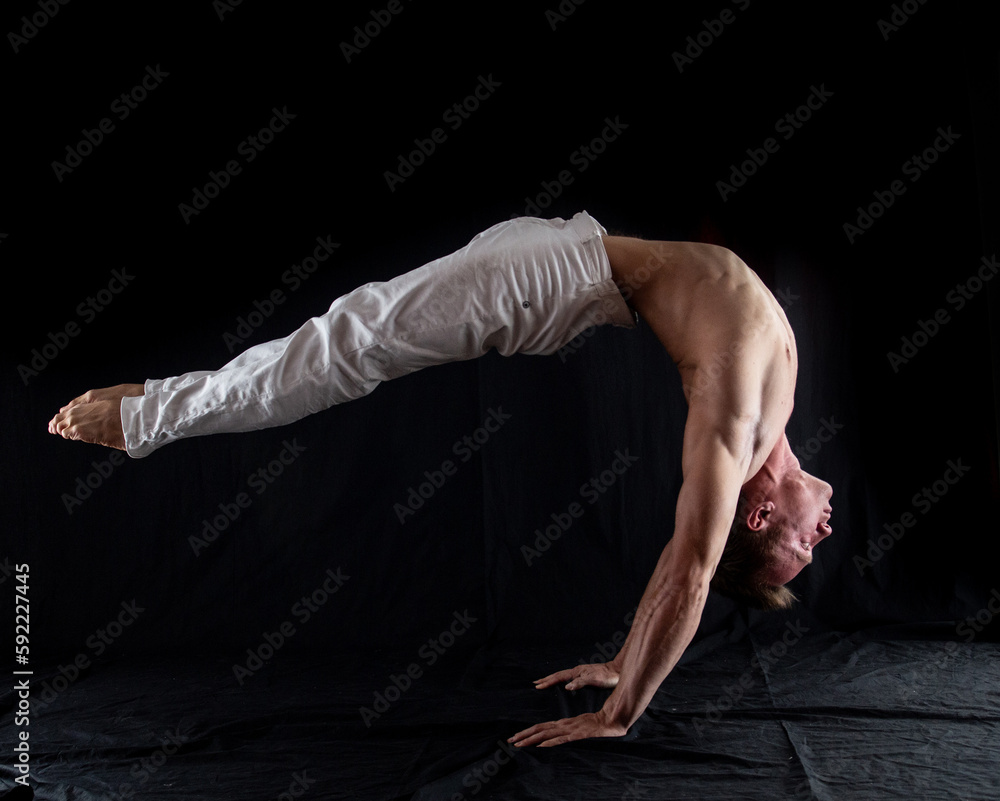 flexible circus artist keep balance on hands on a black background ...