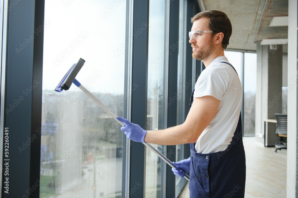An employee of a professional cleaning service washes the glass of the ...
