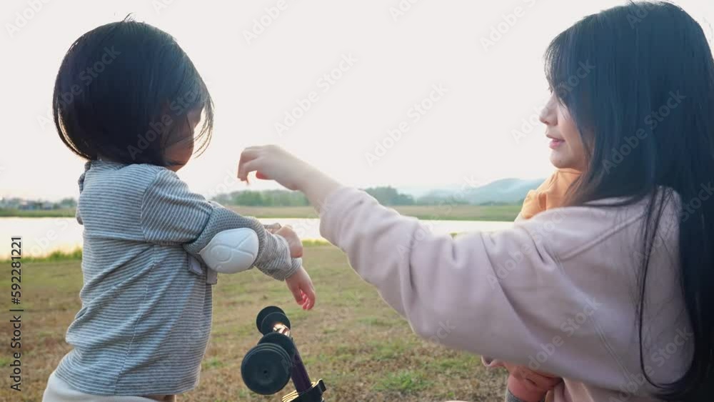 Caring asian young multi tasking mother, helping little adorable ...