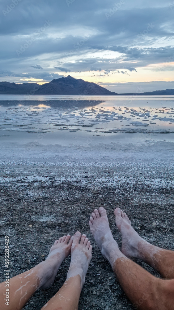 Feet of two people covered with layer of salt with panoramic sunset ...