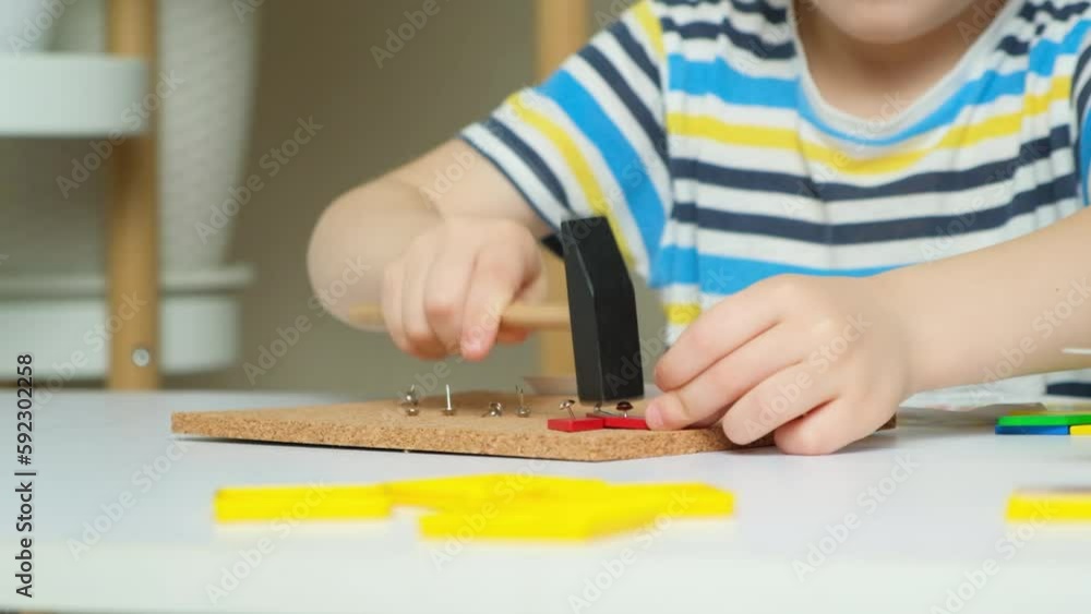 A preschool child plays with a mosaic, builds figures on a board ...