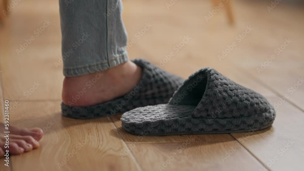 The girl slips her feet into a cozy pair of indoor slippers. As she ...