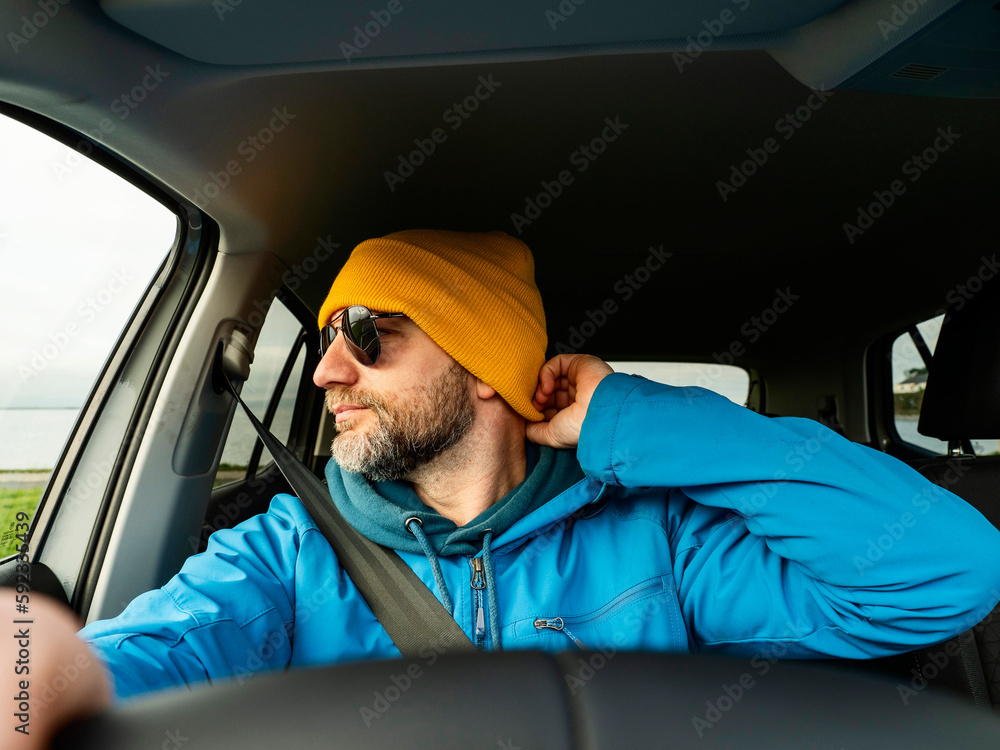 Male driver in a car wearing outdoor blue jacket and yellow hat. Man ...
