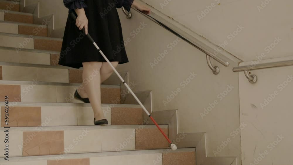 Woman with blindness disability walking down stairs using blind walking ...