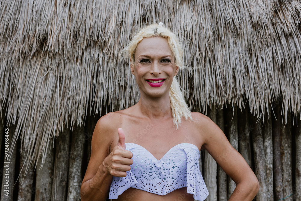 Young transgender latin woman with thumbs up and copy space at the ...