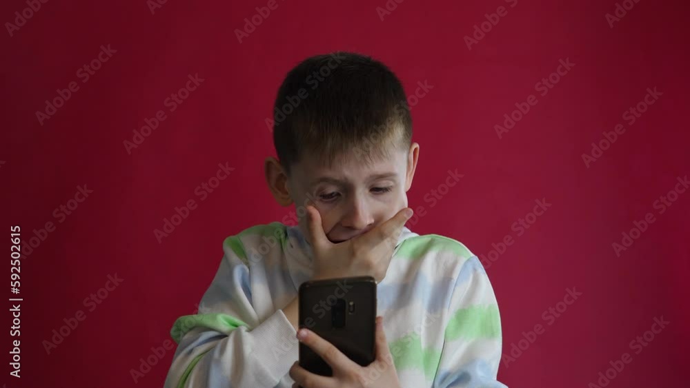 frightened boy 8 years old looks at the screen of a smartphone and ...