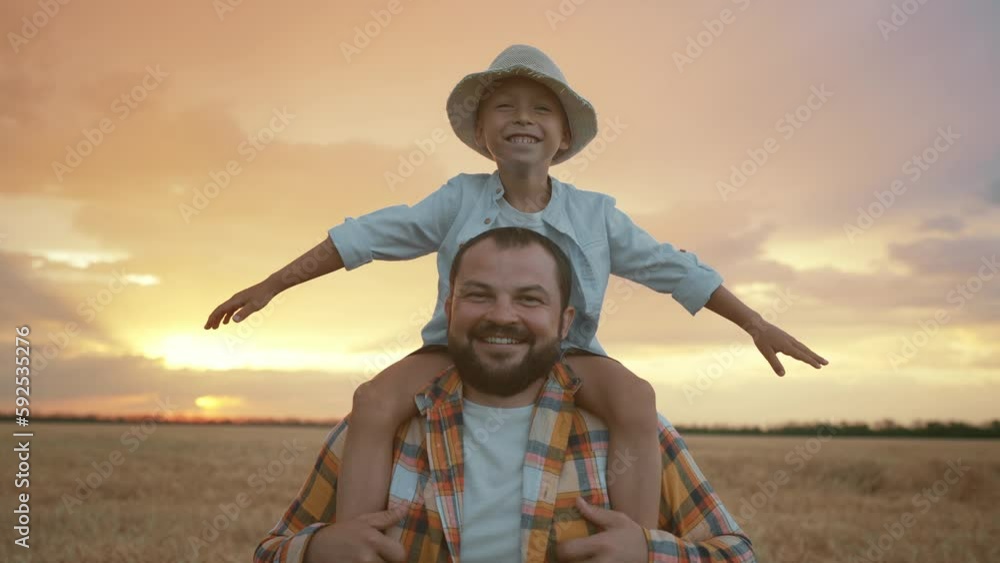 Vidéo Stock Dad holds son on shoulders in wheat field at sunset. Boy ...