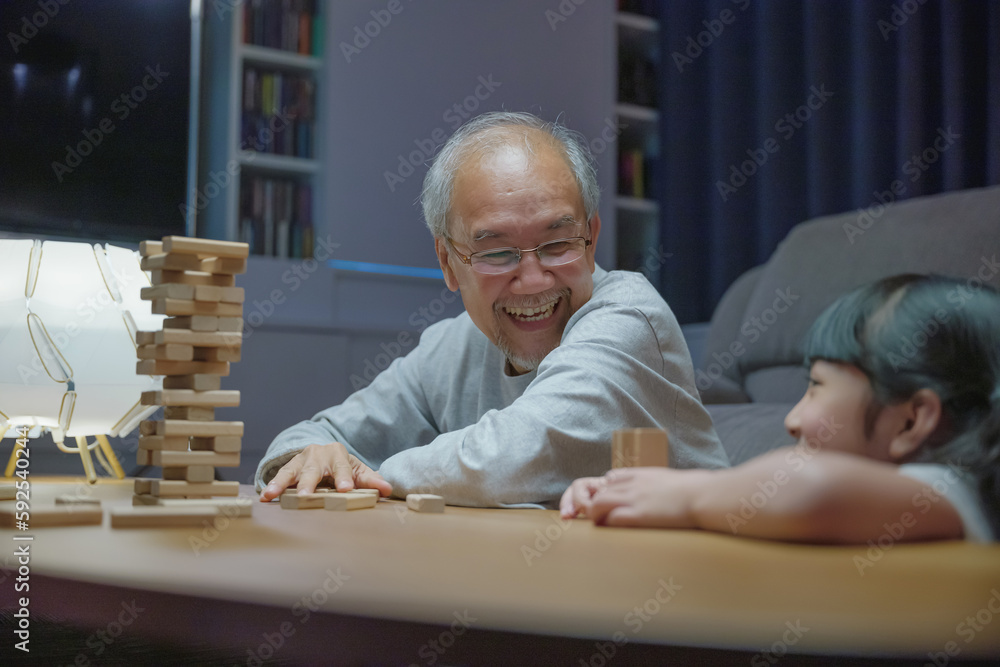 Happy grandparents Asian family enjoy playing toy block with little daughter and mother together ...