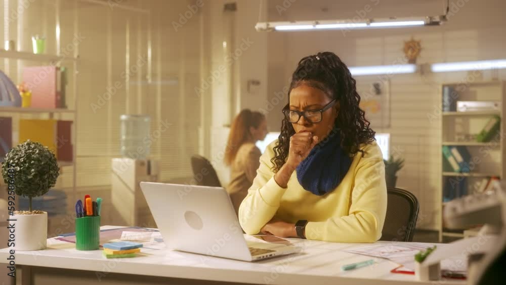 A young African American woman is typing on a laptop keyboard and is ...
